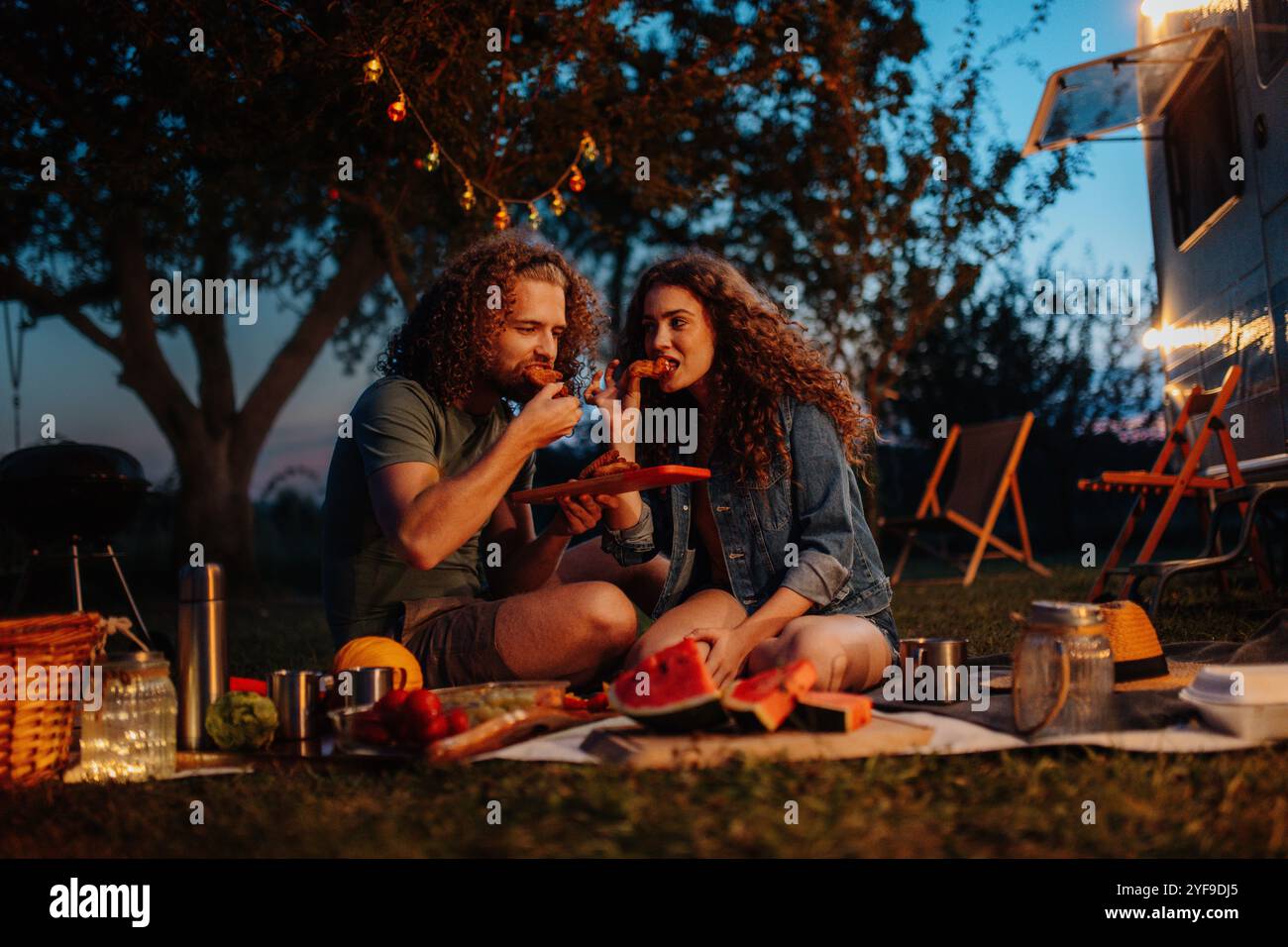 Couple having romantic picnic during camping trip in nature. Caravan ...