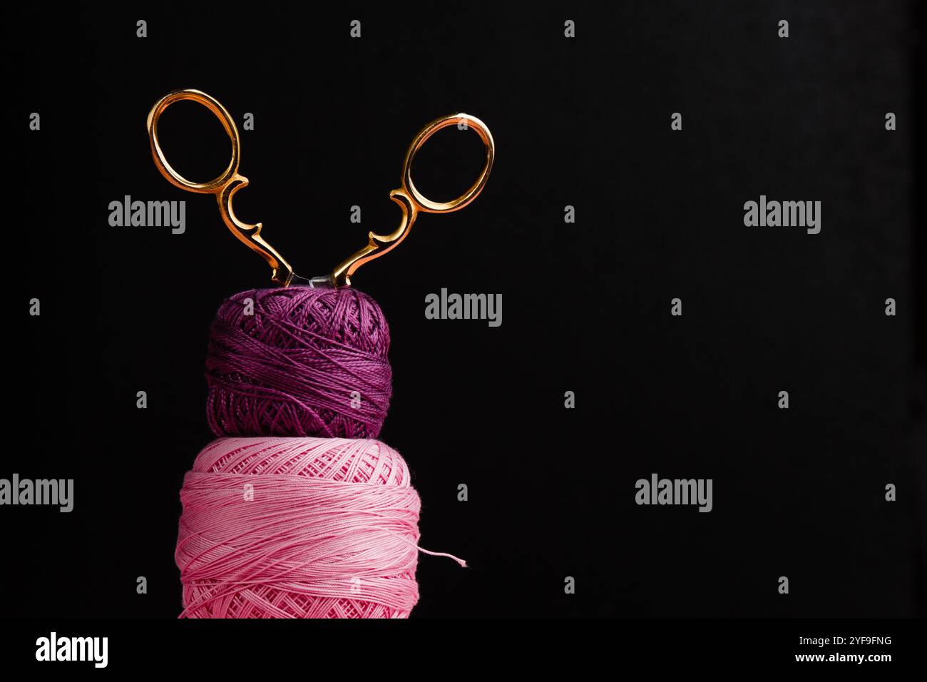 Yarn in skeins of pink and purple shades are stacked on top of each ...