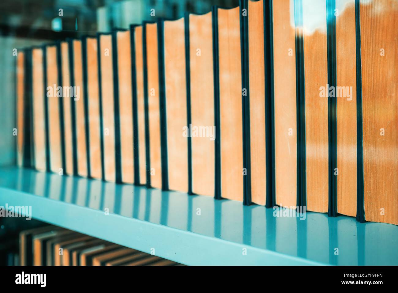 Hardcover books on the shelf in public library seen through the glass ...