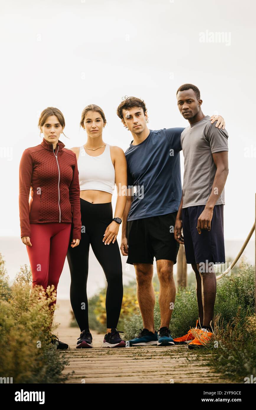 Four friends stand together in athletic clothing on a scenic outdoor ...