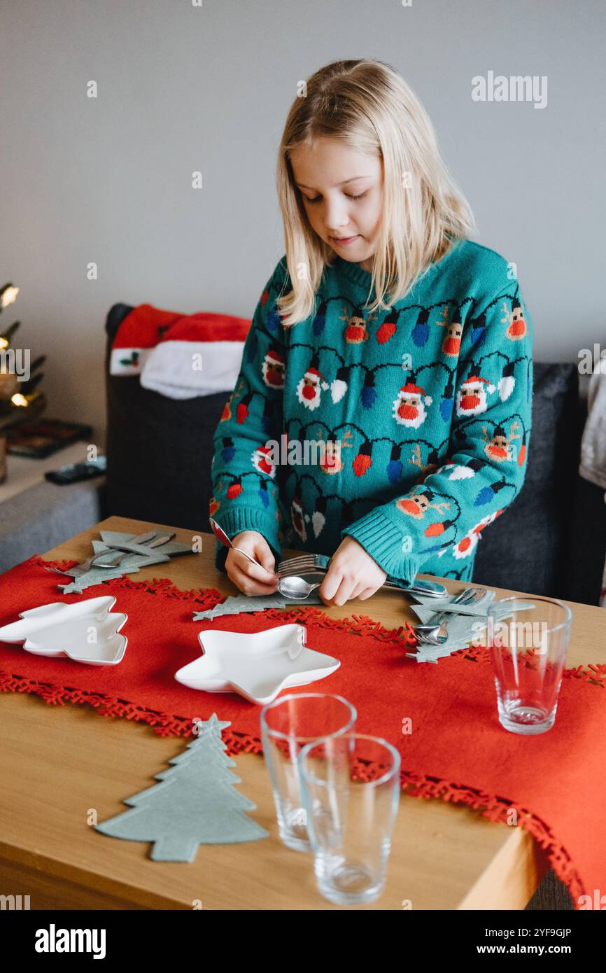 Young girl setting the table for Christmas dinner, holiday traditions ...