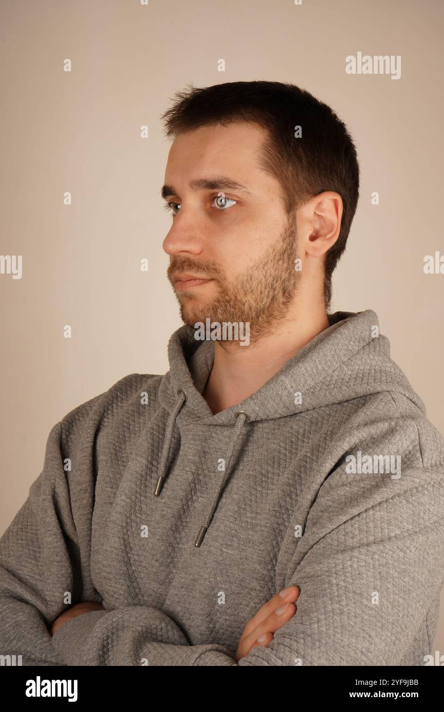 Young male standing in front of camera. Man looking at camera. Crossed ...