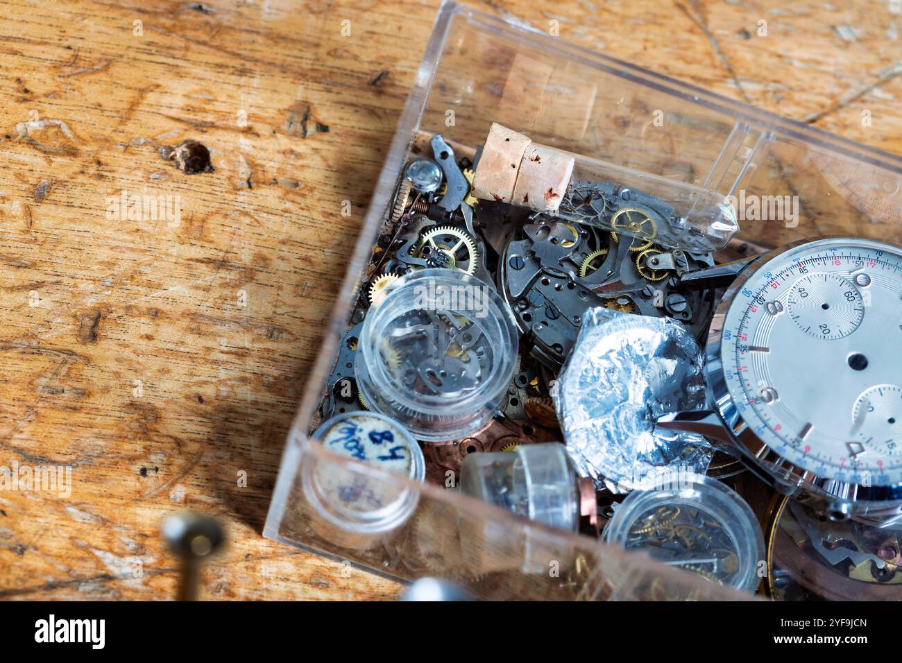 Collection of delicate watch parts, tools, and small gears housed in a ...
