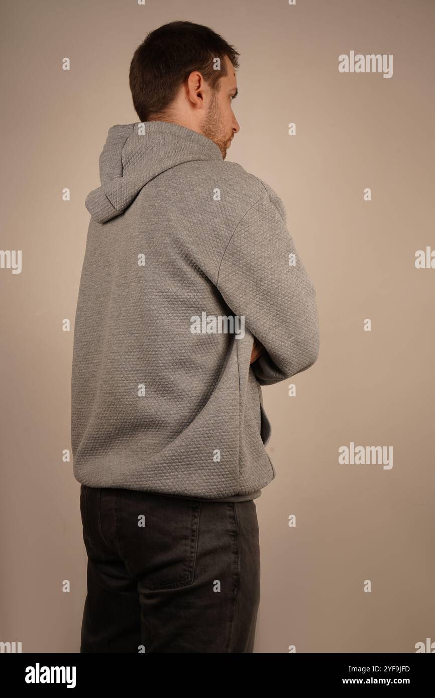 Young male standing in front of camera. Man looking at side. Crossed ...