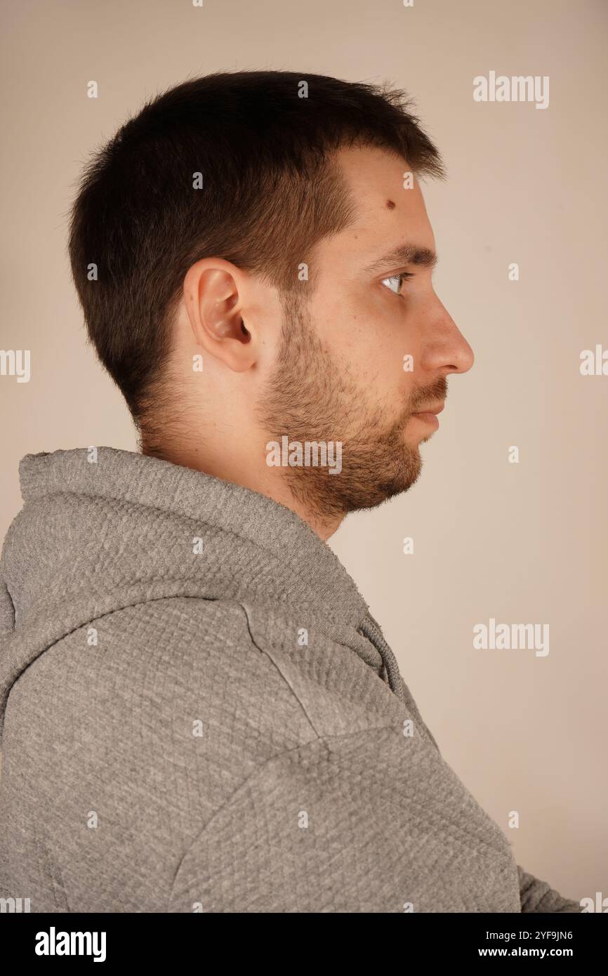 Young man standing in front of camera. Human looking at side. Crossed ...