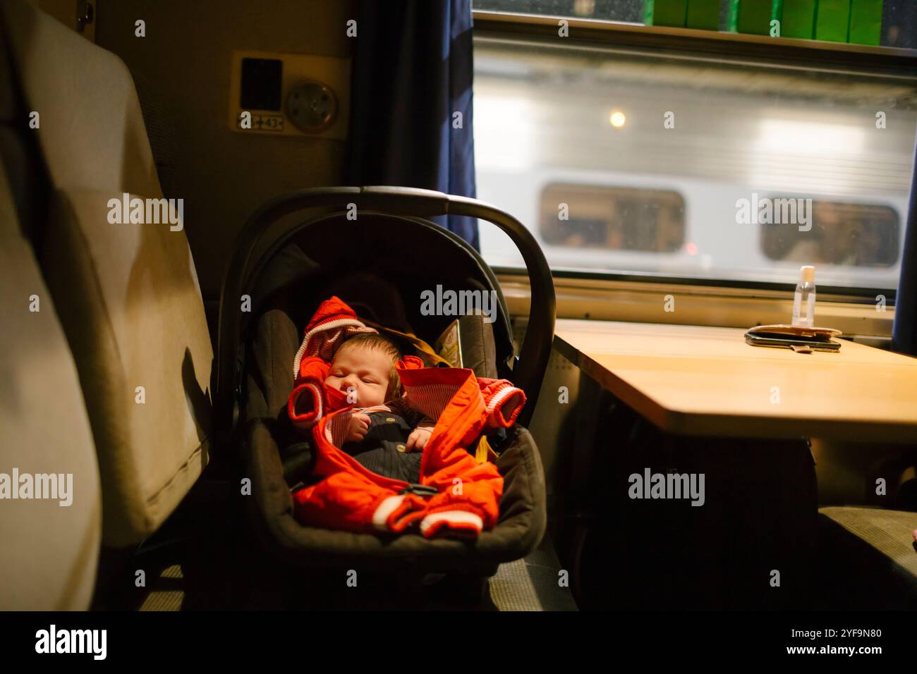 Boy sleeping inside baby seat in train Stock Photo - Alamy