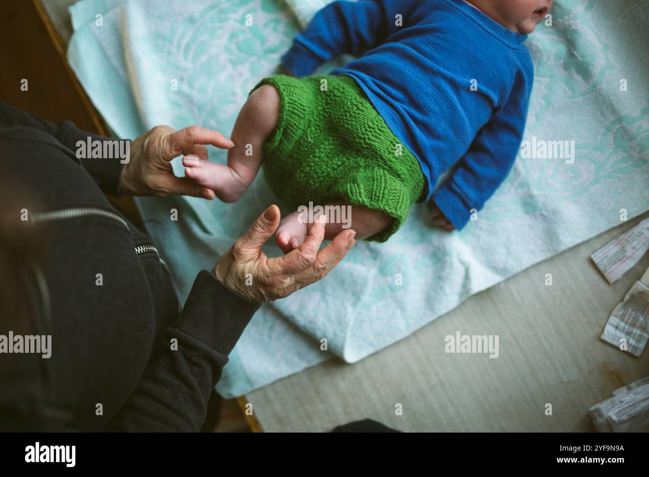 Senior woman holding feet of newborn baby lying down Stock Photo - Alamy