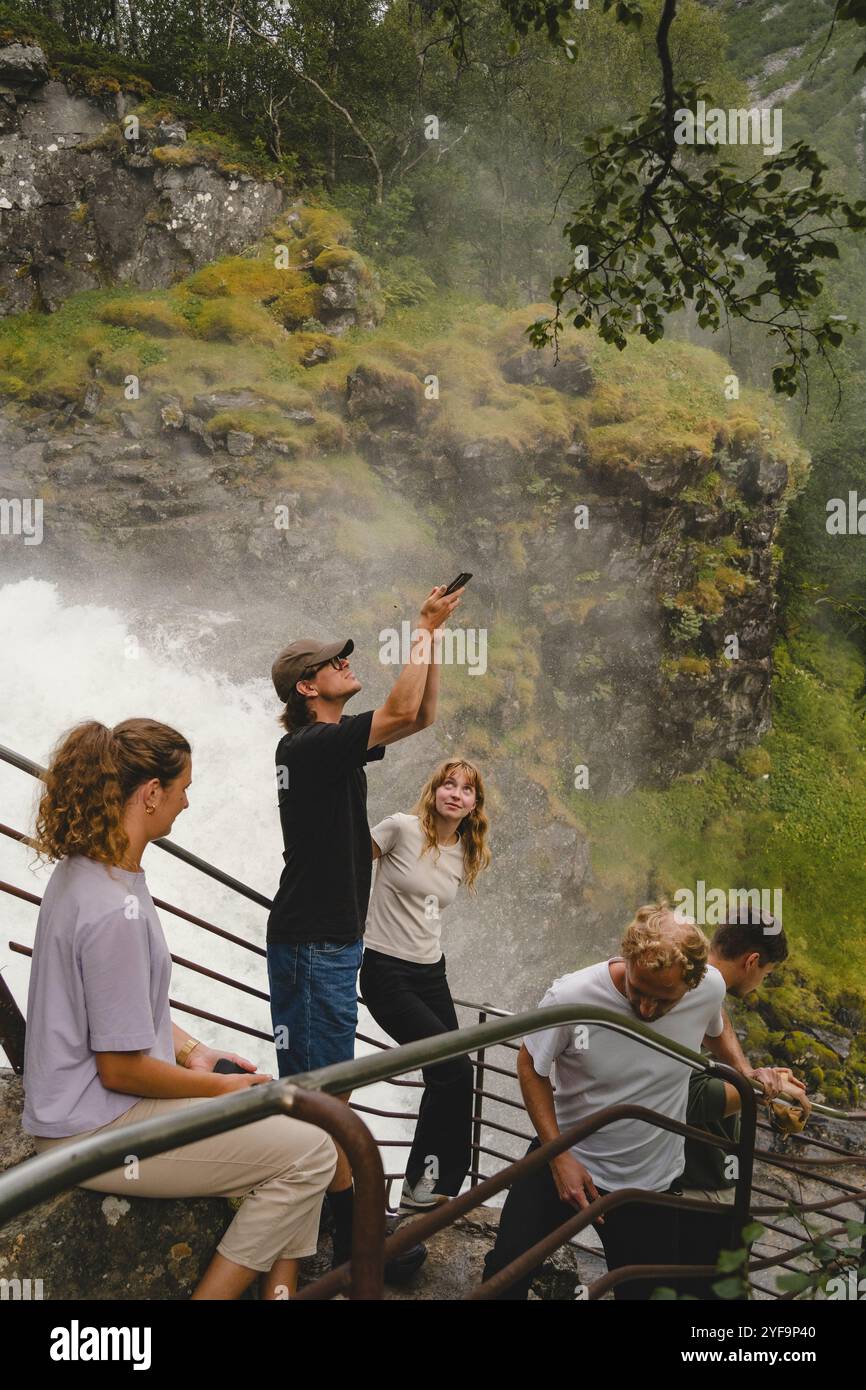 Low angle view of man photographing waterfall with friends from ...
