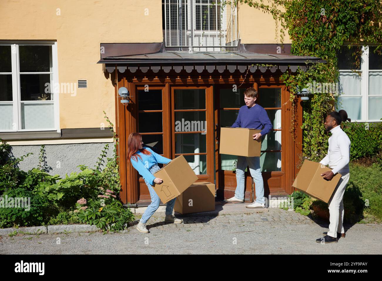 Male and female friends holding boxes and helping each other during ...