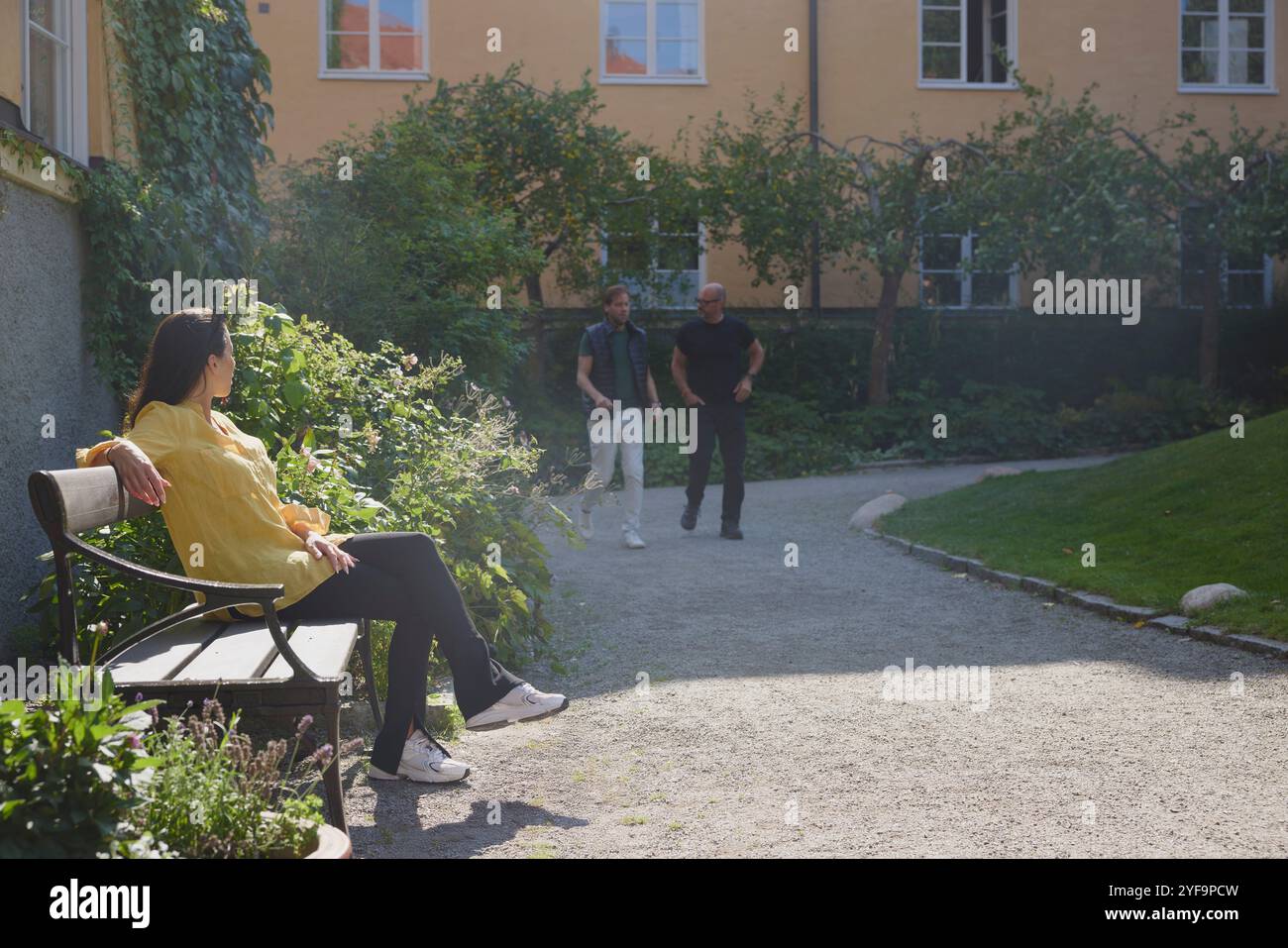 Woman sitting with legs crossed at knee on bench while looking at male ...