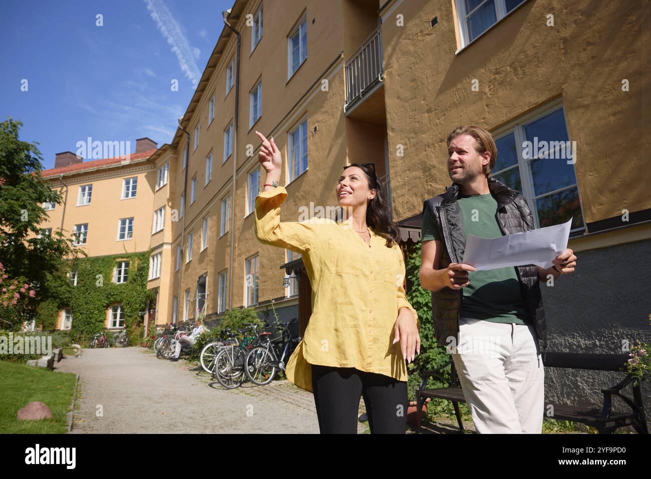 Female architect pointing while walking with male colleague holding ...