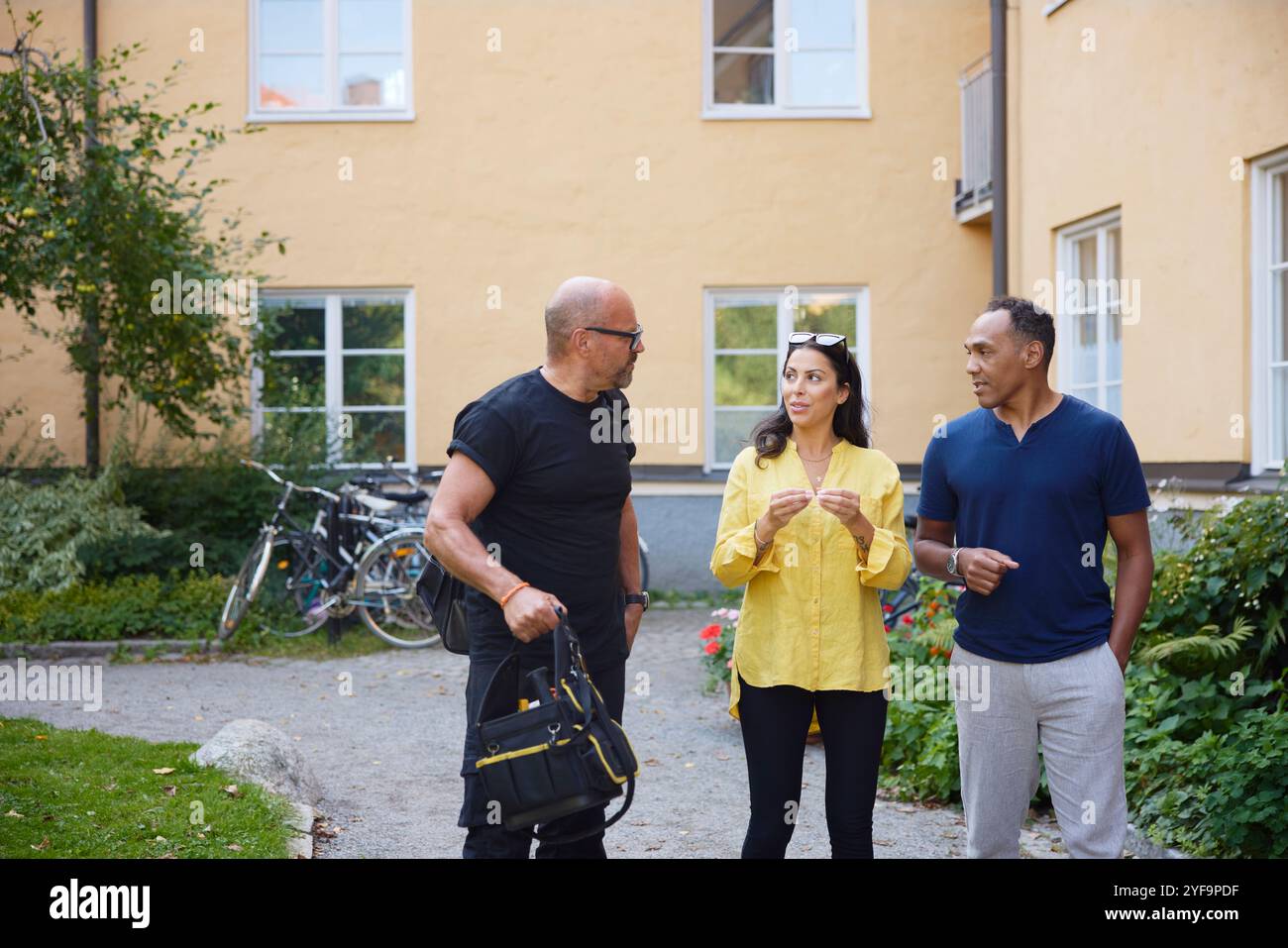 Male and female neighbors talking with repairperson outside building ...