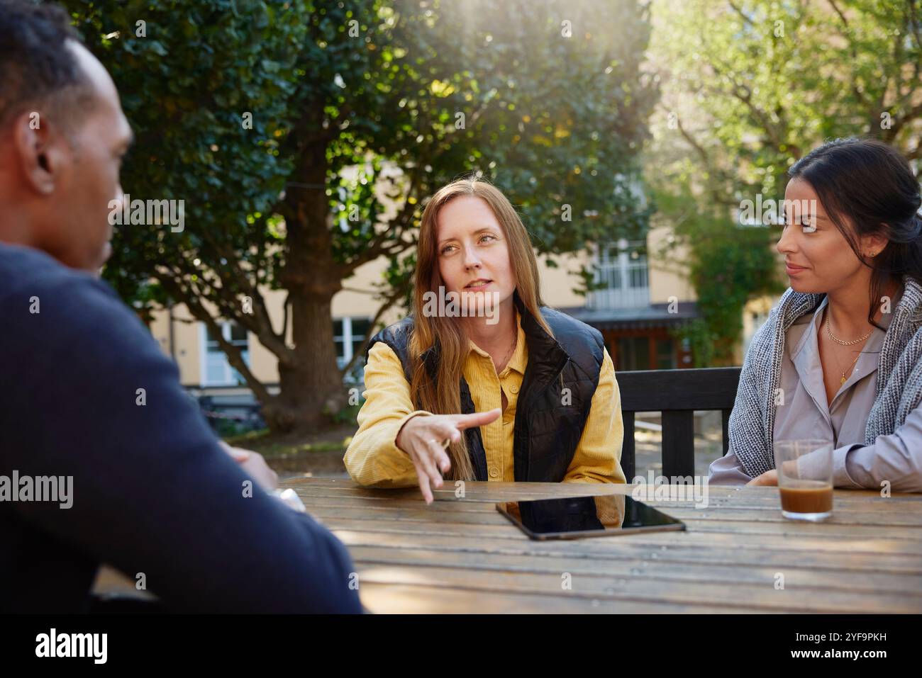 Female building contractor explaining couple sitting on bench in garden ...