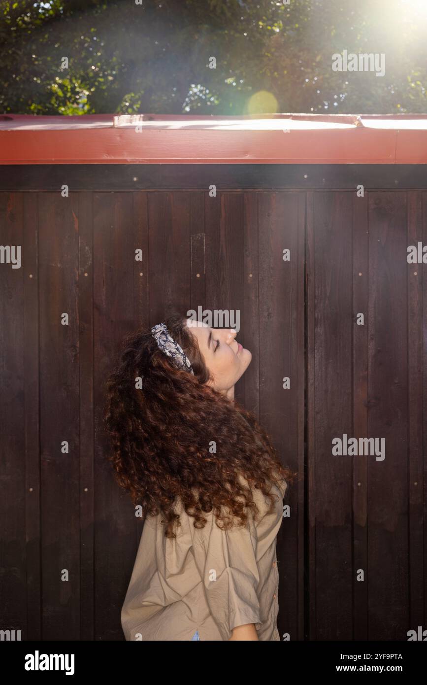 Sunlight falling on young woman against brown wall Stock Photo - Alamy
