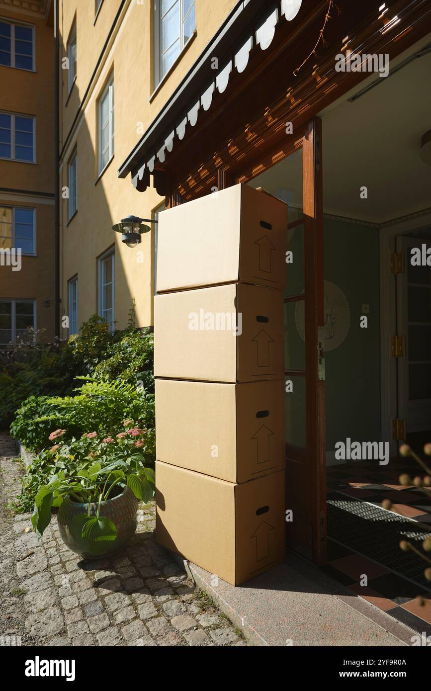 Stack of cardboard boxes by potted plants at building entrance Stock ...