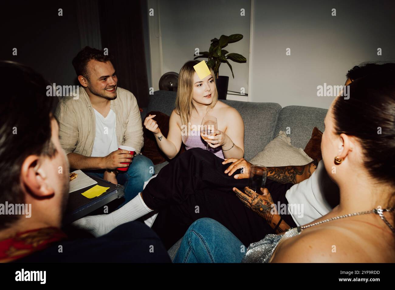 Group of friends playing guessing game during party at home Stock Photo ...
