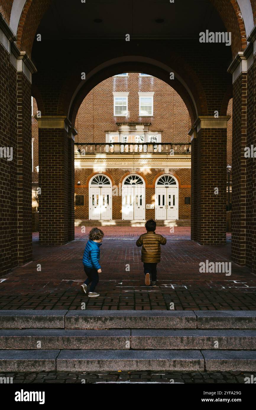 Two toddler brothers run in brick courtyard of urban Stock Photo - Alamy