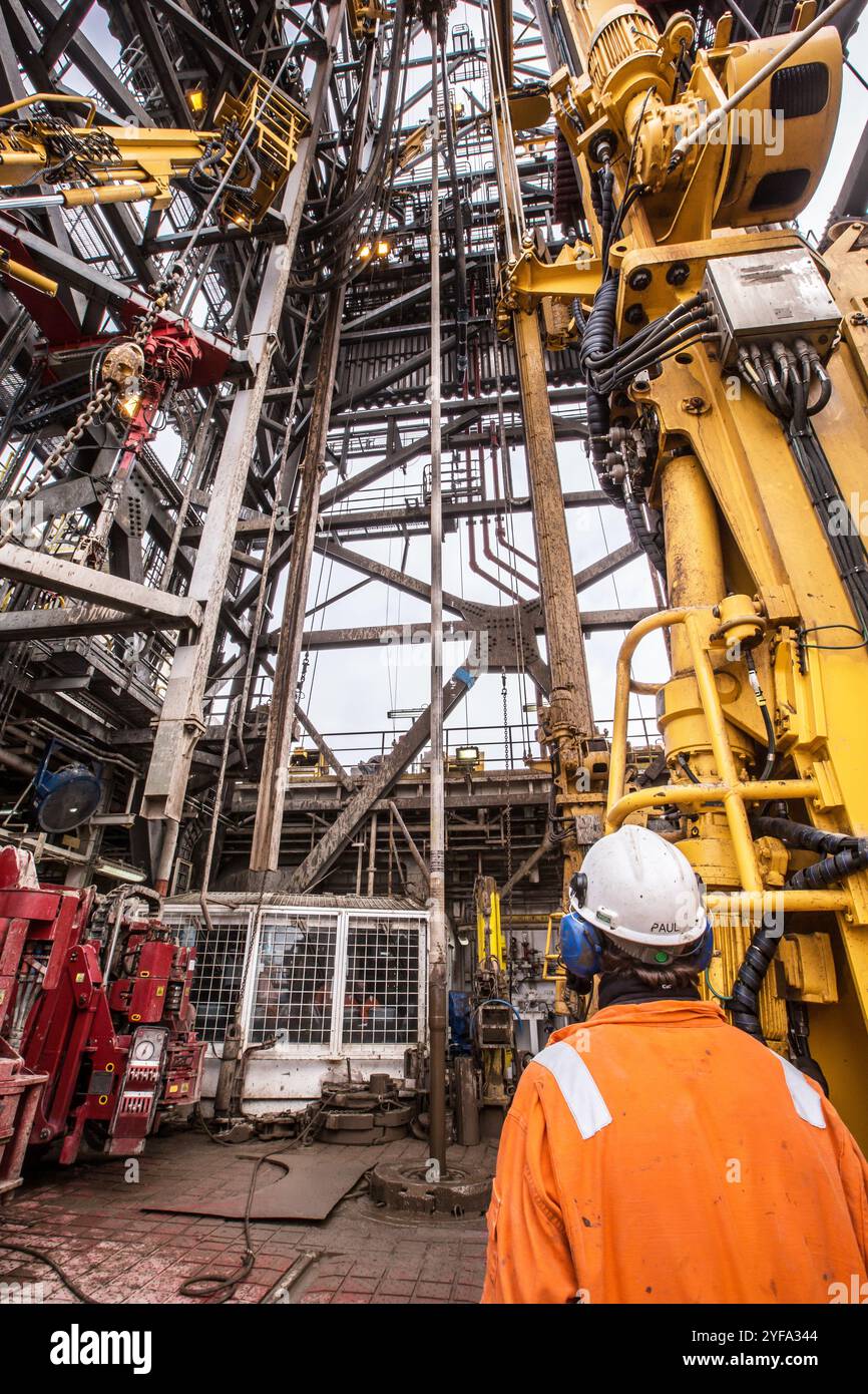 Oil worker looking up the derrick of a drilling rig in the north sea ...