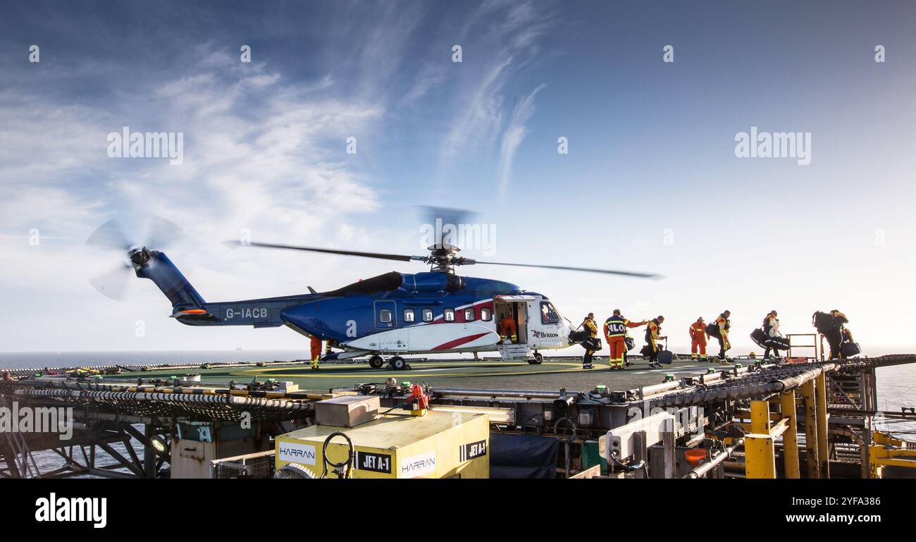 Helicopter on the helipad of an offshore oil rig with oil workers ...