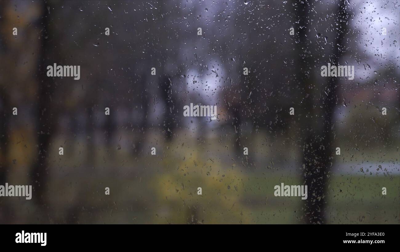 A view through a rain-streaked window. Raindrops adorn a window pane on ...