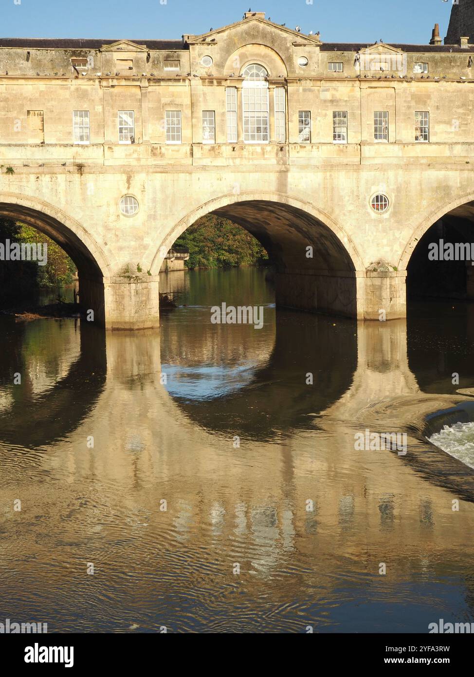 The arches of Pulteney Bridge reflected in the waters of the River Avon ...