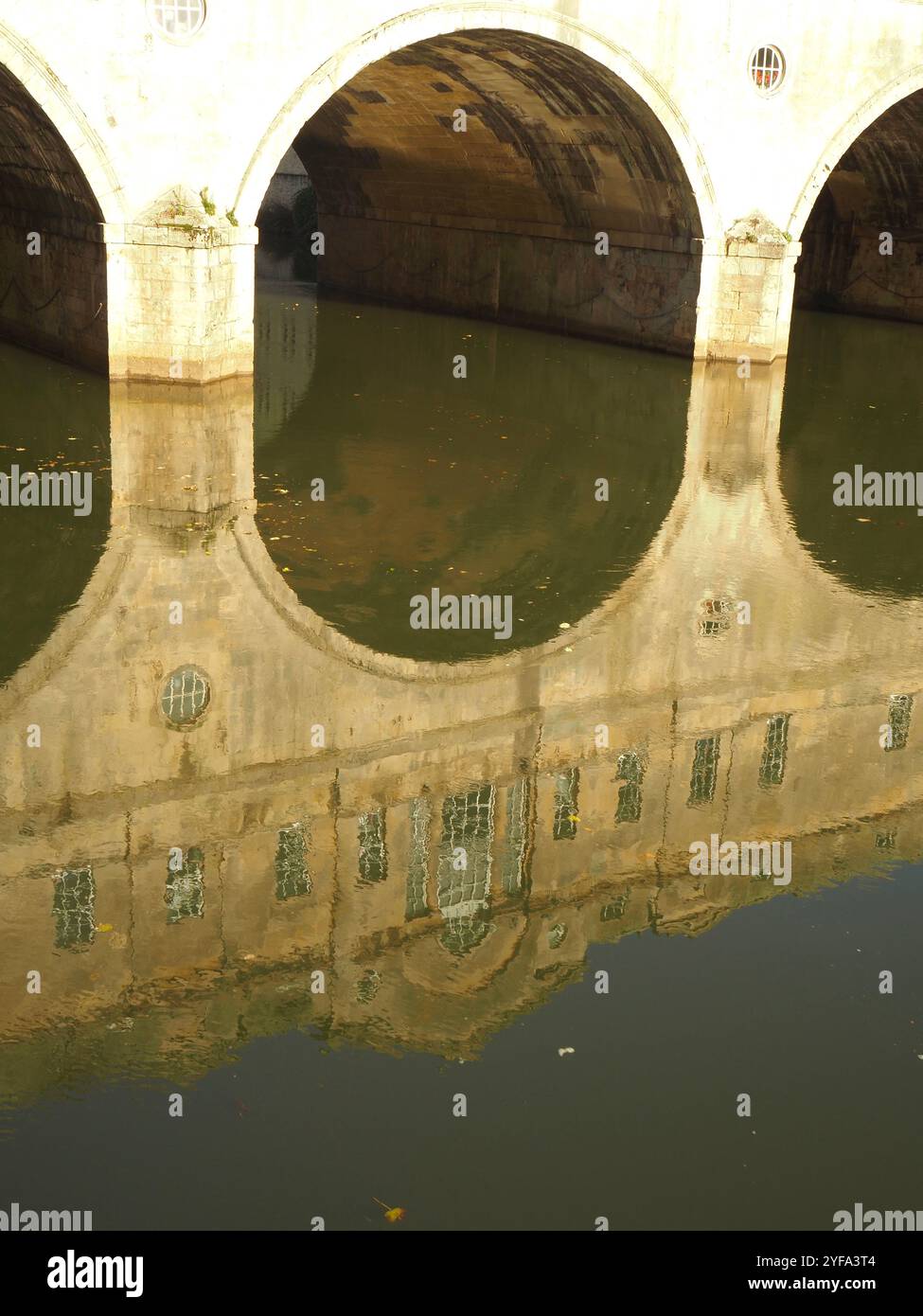 The arches of Pulteney Bridge reflected in the waters of the River Avon ...