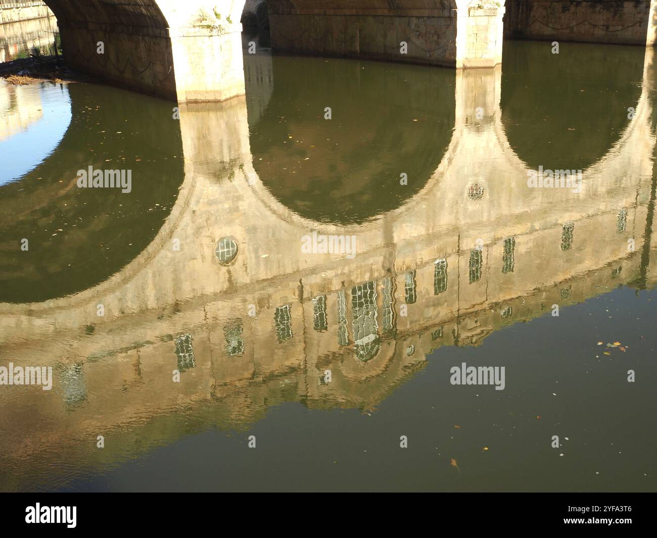 The arches of Pulteney Bridge reflected in the waters of the River Avon ...