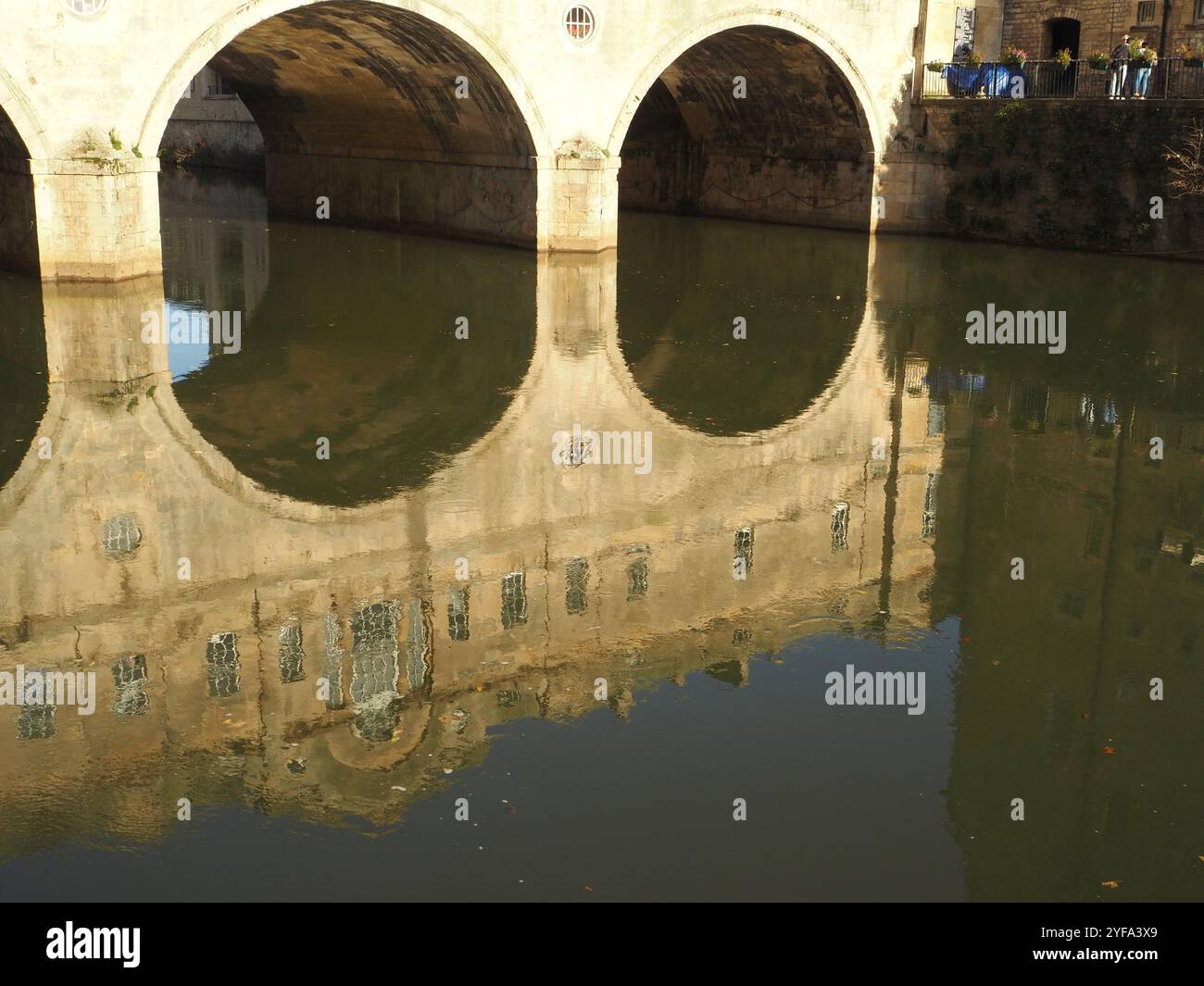 The arches of Pulteney Bridge reflected in the waters of the River Avon ...