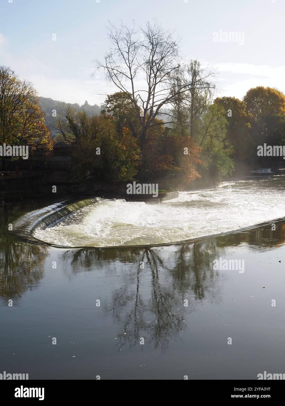 Pulteney weir, in spate after heavy rain with autumn trees behind ...
