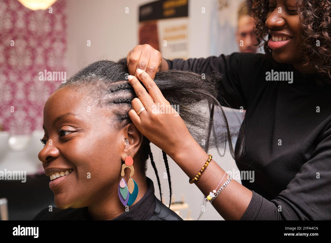 Hairdresser braiding crochet braids on client in afro hair salon Stock ...