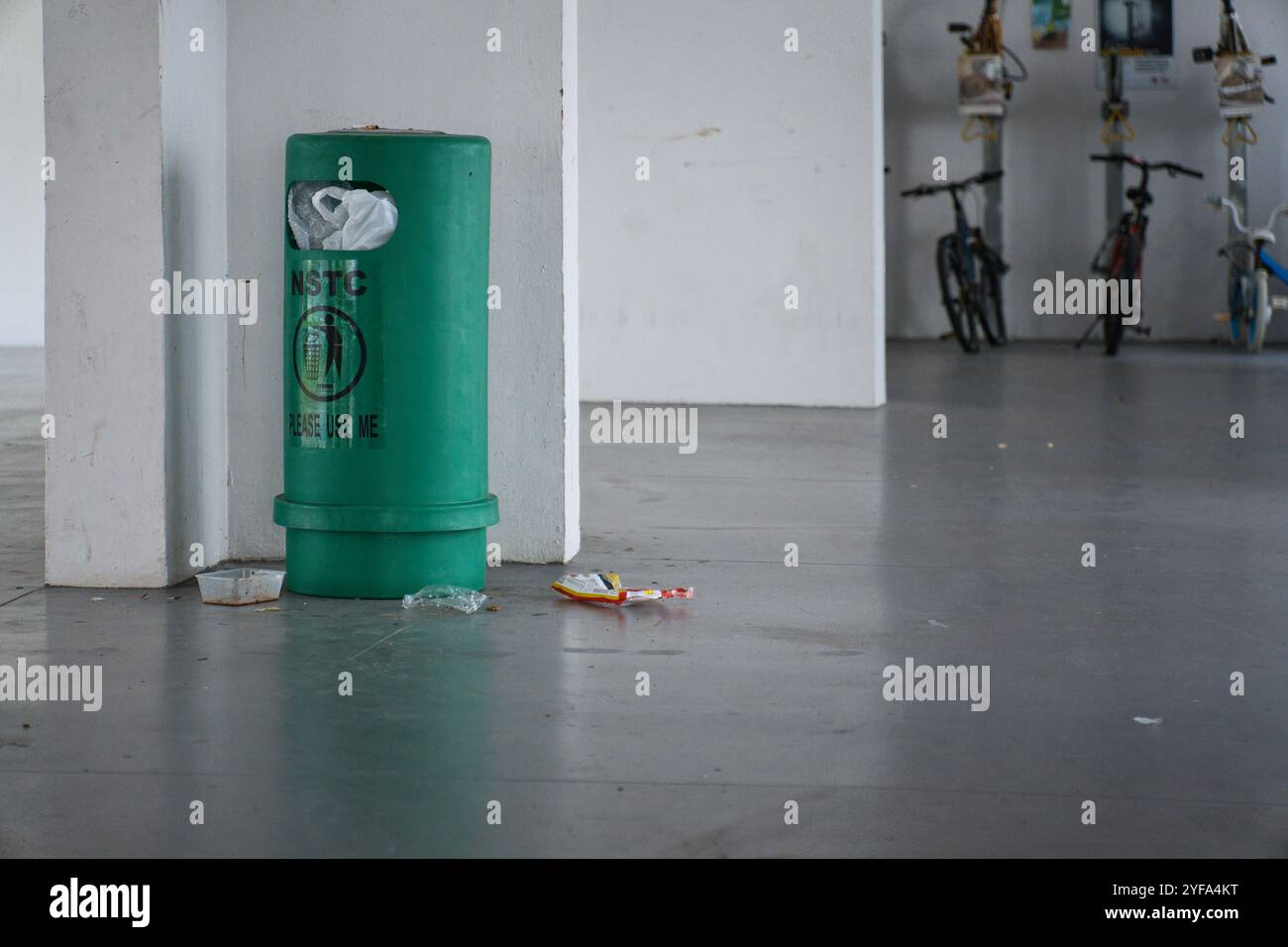 Overflowed litter bin with rubbish thrown outside the bin on the ground ...