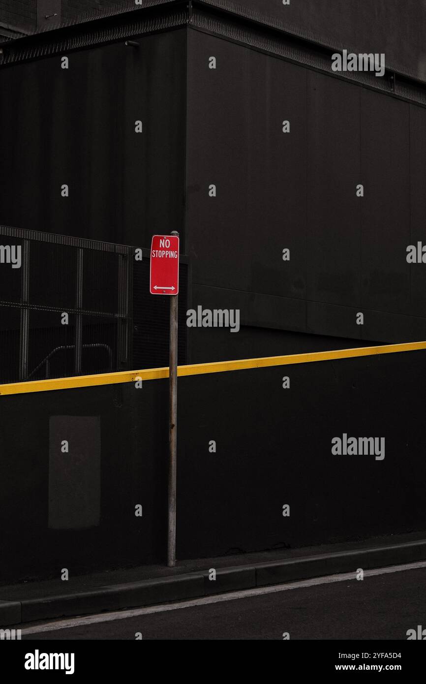 A red No Stopping sign against a series of intersecting black painted ...