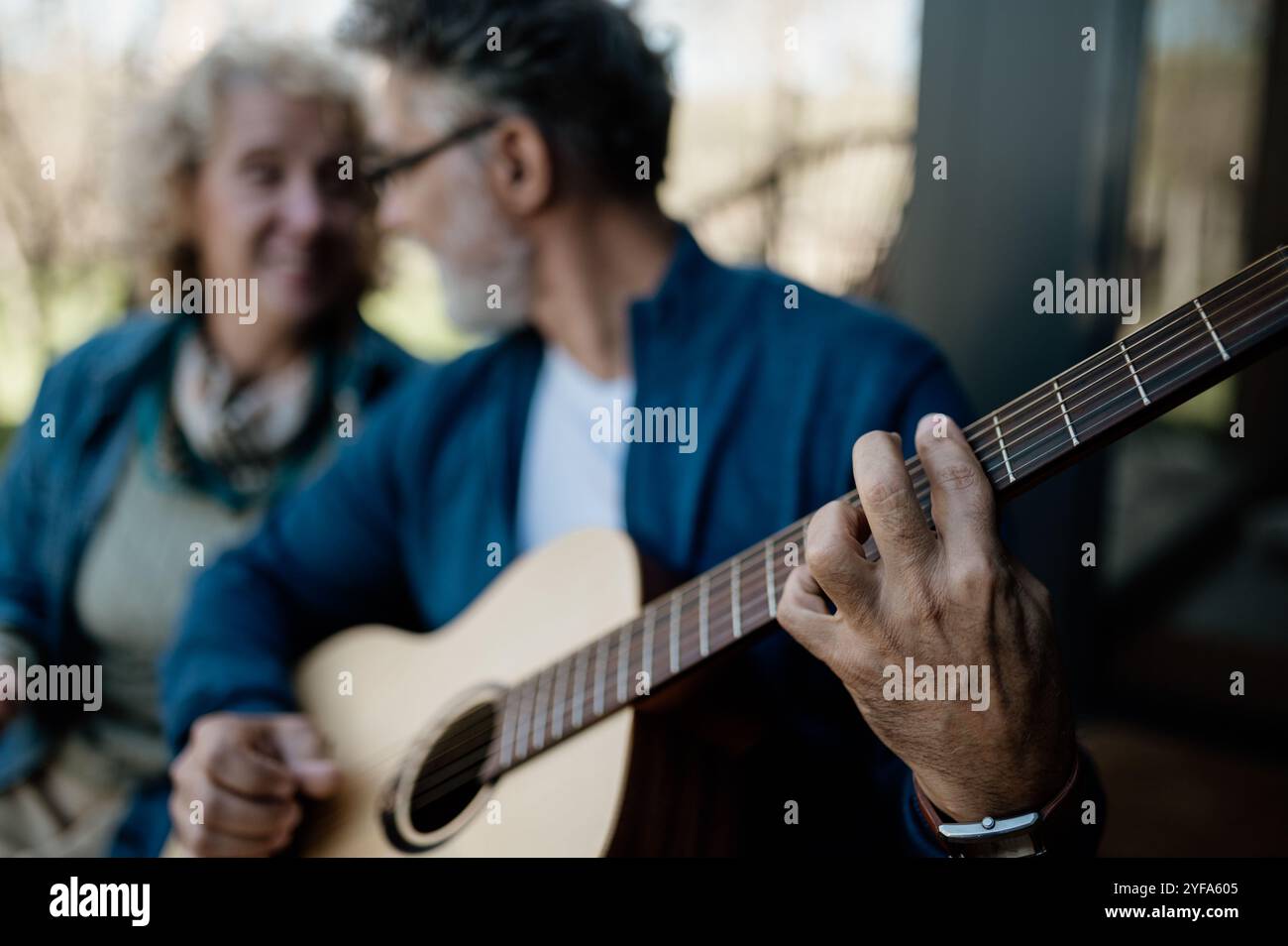 Man playing an accoustic guitar with his woman in background Stock ...