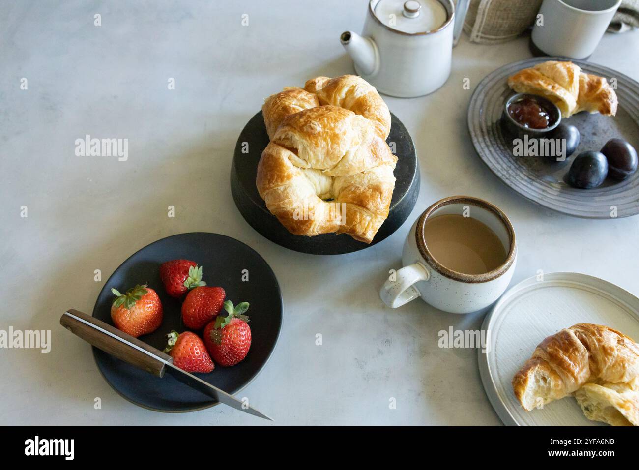Breakfast table with croissants, coffee, strawberries, and plums Stock ...
