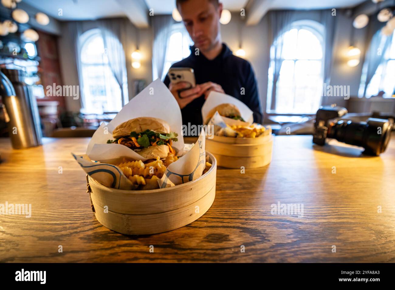 Person taking a photo of gourmet burgers and fries in a stylish ...