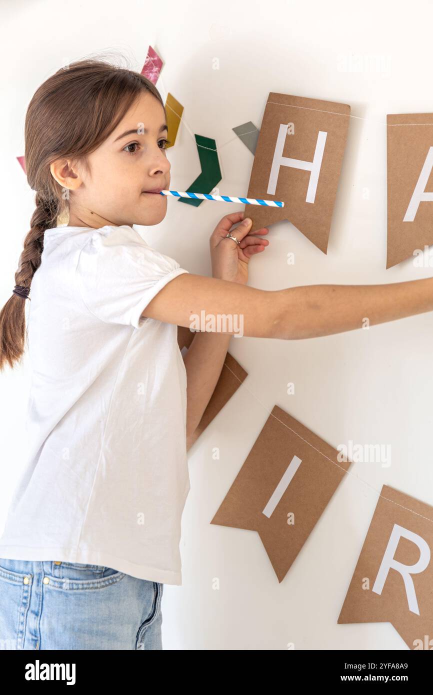 Preparation for the birthday. Girl hangs Happy Birthday sign on a wall ...