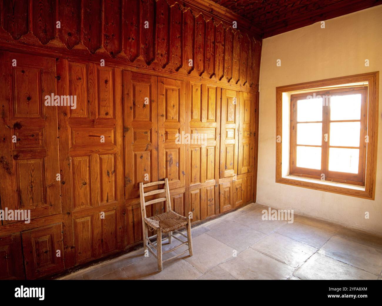 Empty room with wooden wall one chair on the floor, and bright sunshine ...