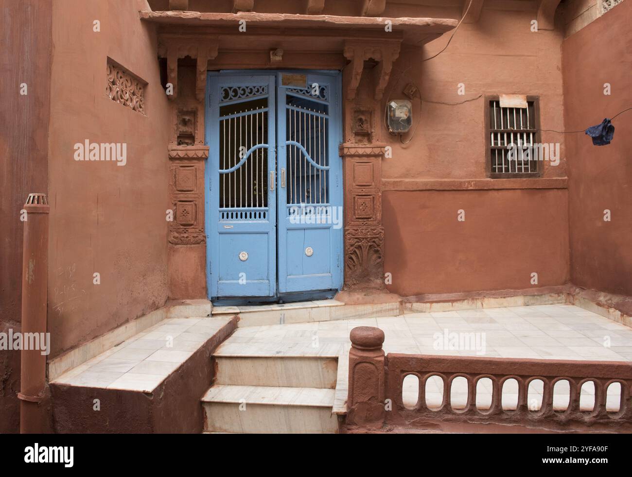 Facade of a traditional Indian red house courtyard with blue door ...