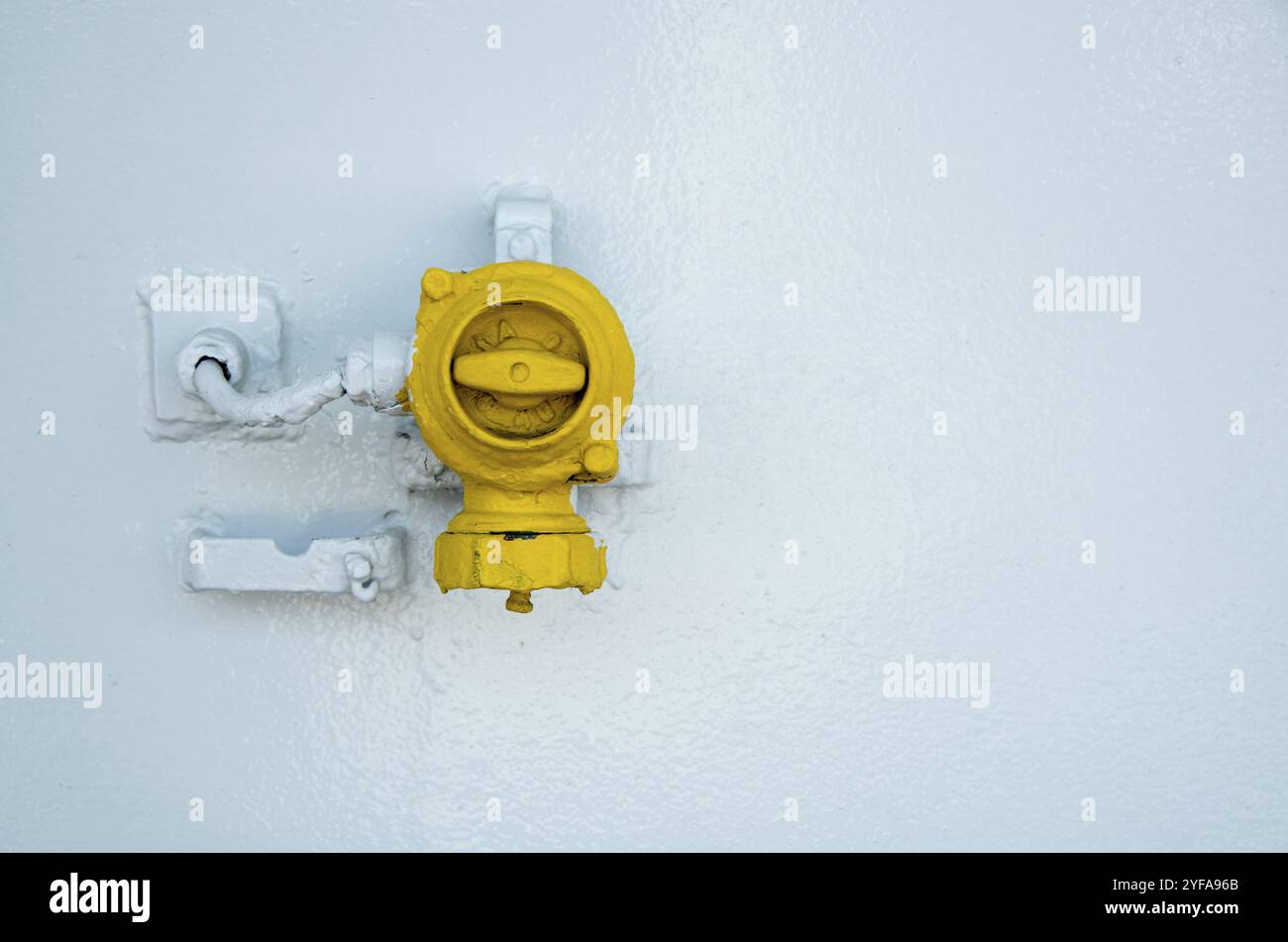 Yellow control valve industrial switch on a white metallic surface ...