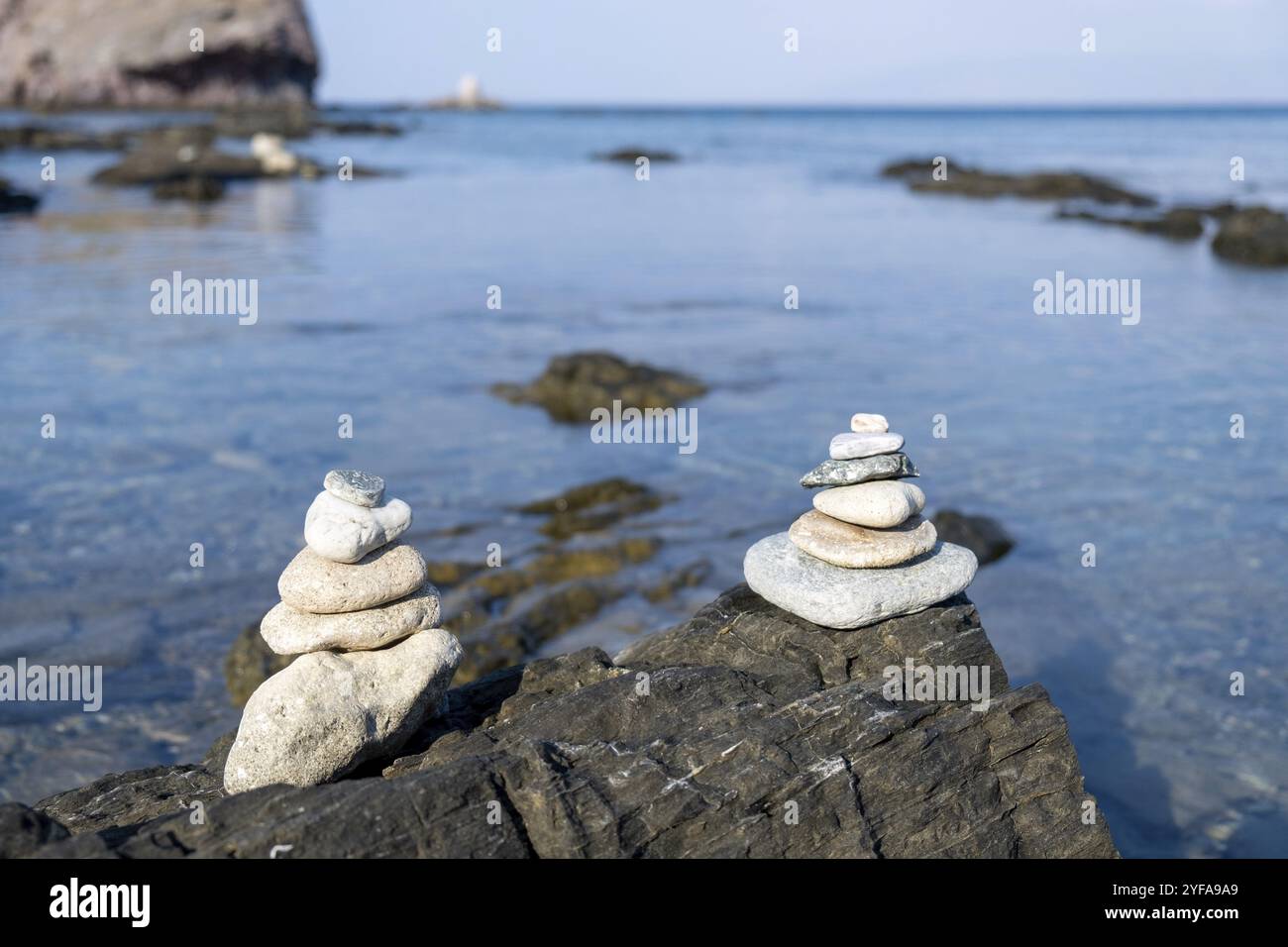 Pyramid of balancing white pebbles, on the rock of a rocky beach ...