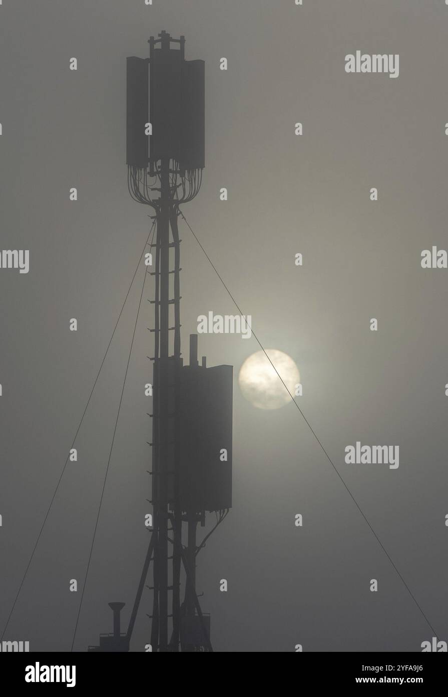 Communication tower on a building with 4G 5G antenna at sunrise in mist ...