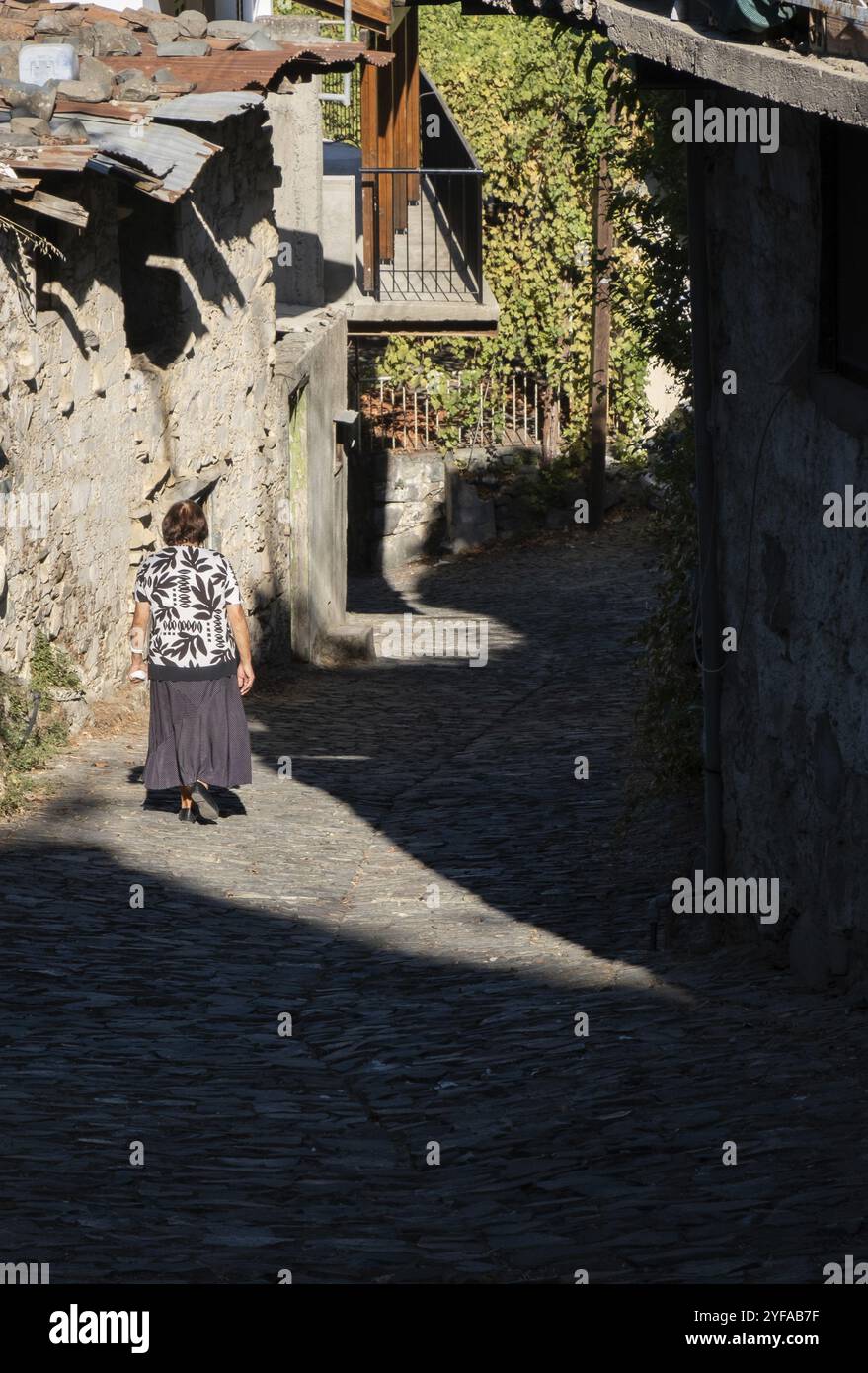 Senior woman walking in the stoned street of a traditional village ...