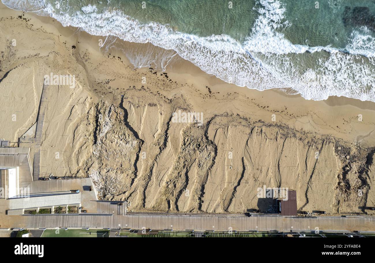 Aerial view of ocean waves breaking on a sandy beach. Beach erosion after coastal flooding ...