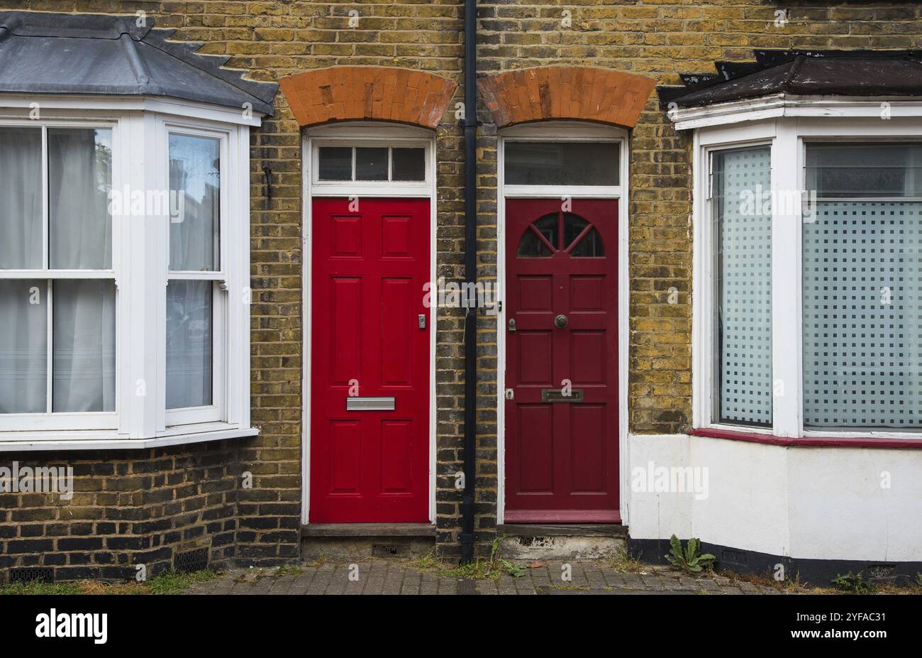 Traditional English house front entrance with red closed doors and ...