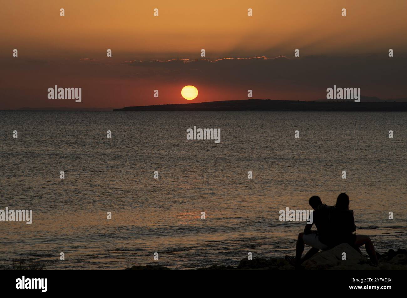 Silhouette of young couple enjoying beautiful sunset at the beach ...