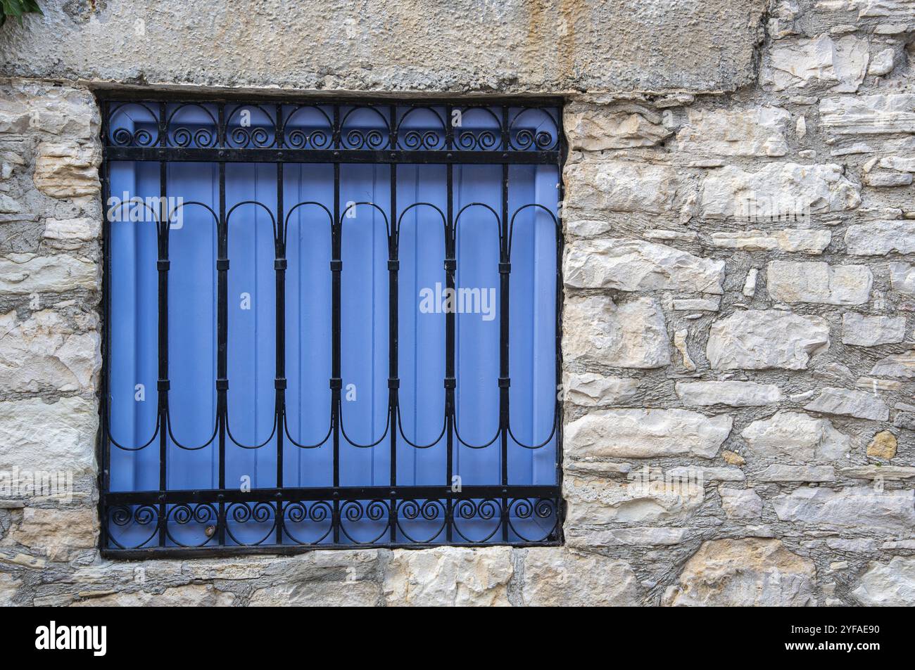 Blue wooden vintage window with a metal safety frame on a white brick ...