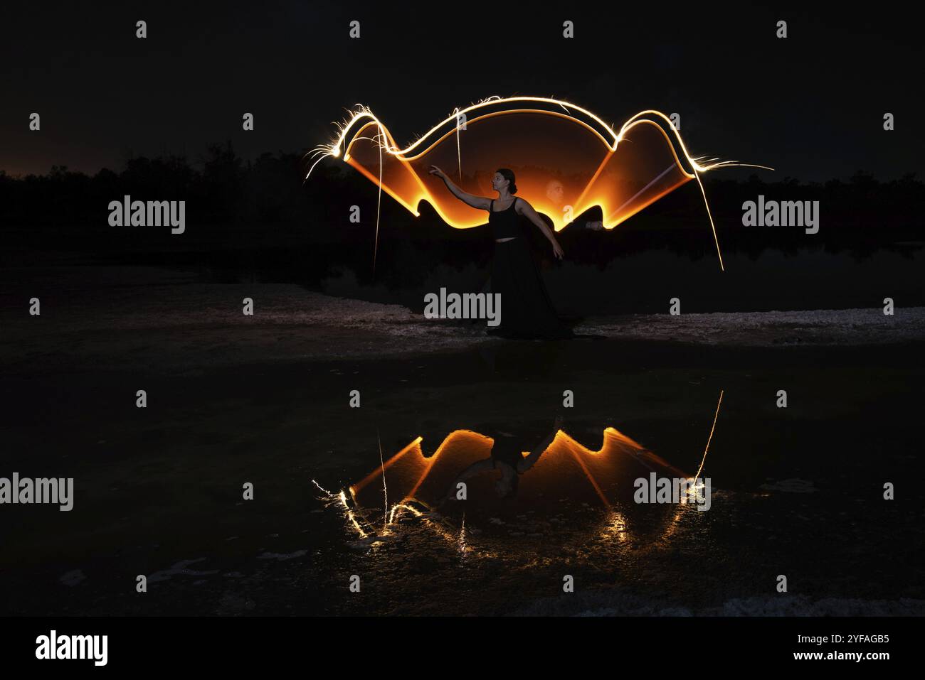 Woman posing for lightpainting photos with bright lights in the dark ...