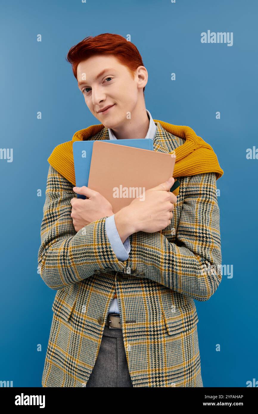 A confident student dressed in a stylish layered outfit holds his ...