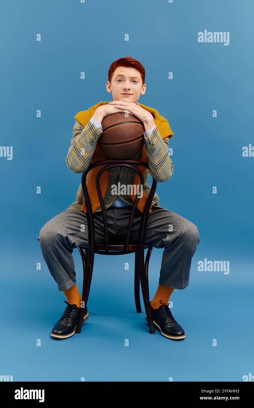 A confident young man in a layered winter outfit balances a basketball ...