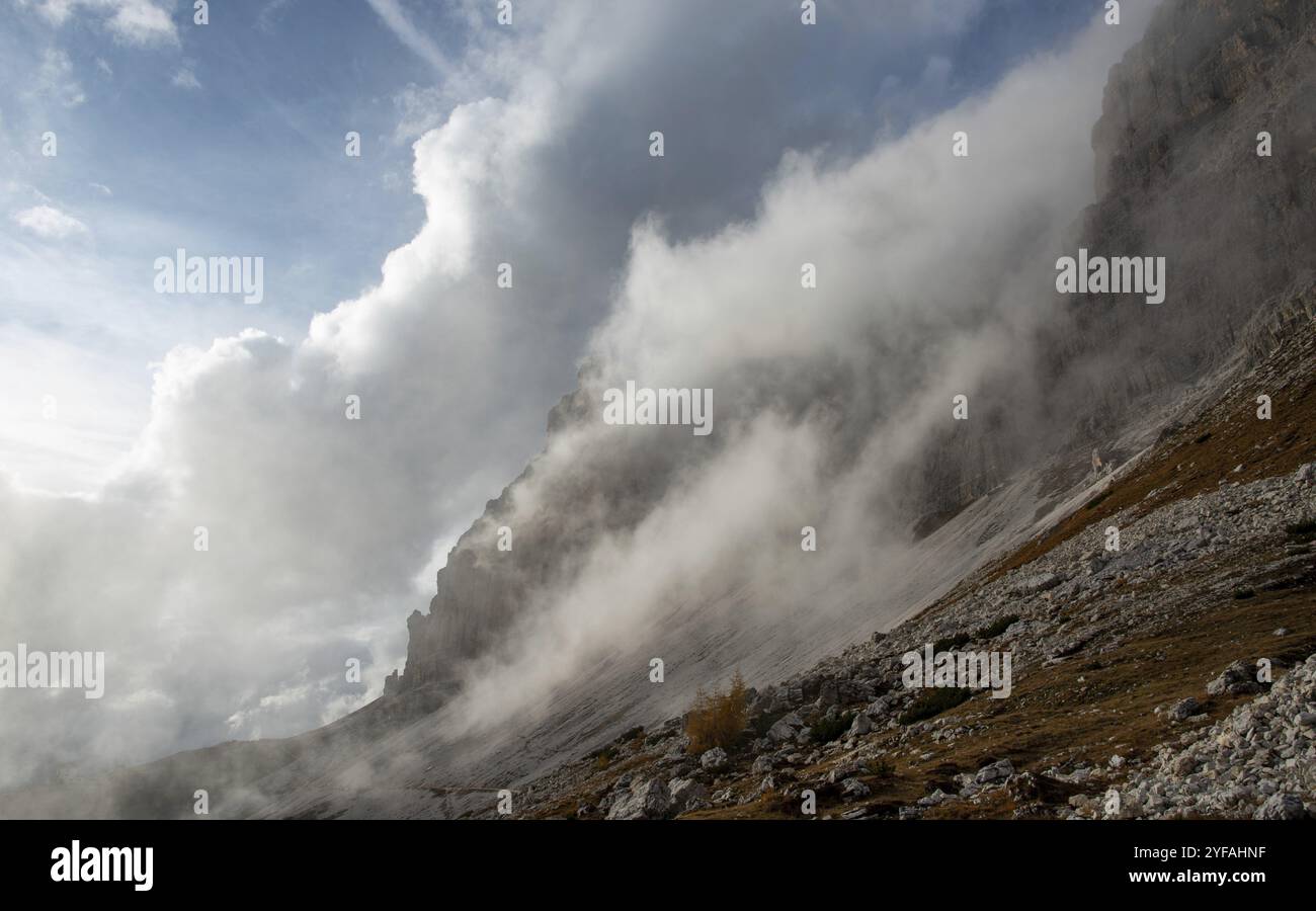 Cloudy fogy sky mountain peaks covered in mist in the morning. Dolomite ...